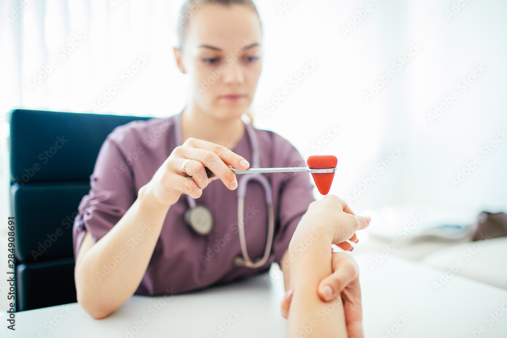 Neurological examination. The neurologist testing hand reflexes on a ...