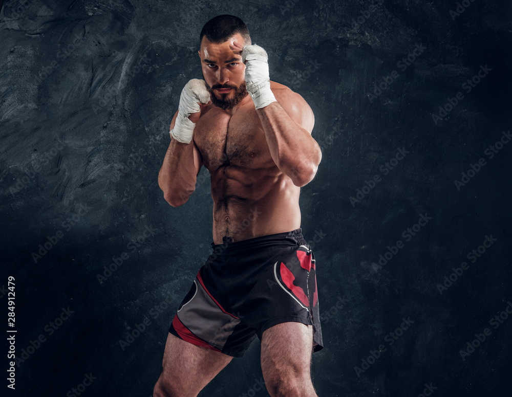 Strong muscular fighter is showing his punch while posing for ...