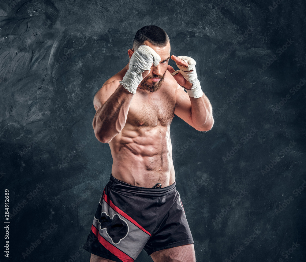 Strong muscular fighter is showing his punch while posing for ...