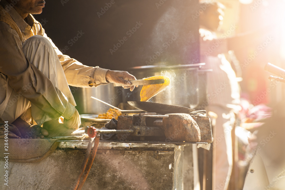 An Indian elderly man is cooking Chapati on the streets of Jaipur ...