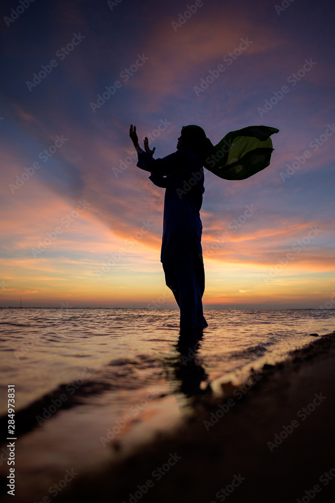 Muslim Girl saying prayer by the beach with sunset Stock Photo | Adobe ...