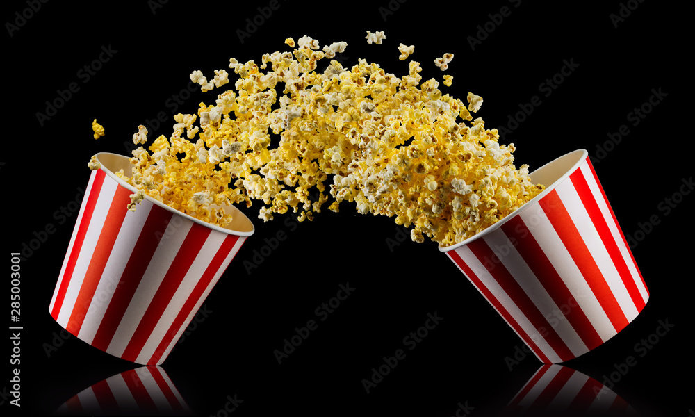Flying popcorn from one striped bucket to another isolated on black ...
