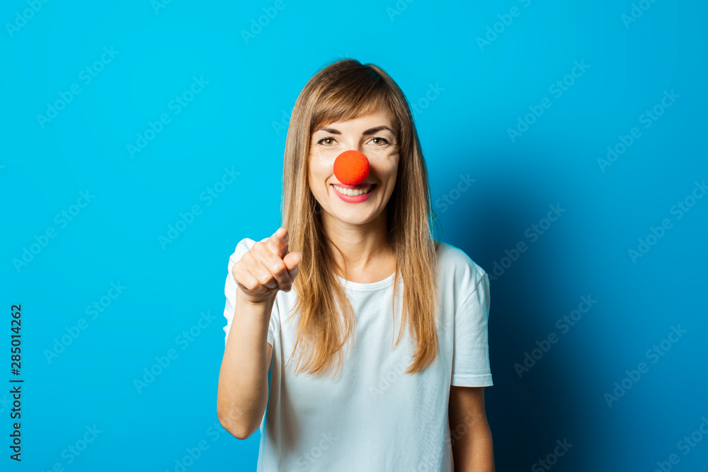 Beautiful young woman in a white T-shirt and a red clown nose smiles ...