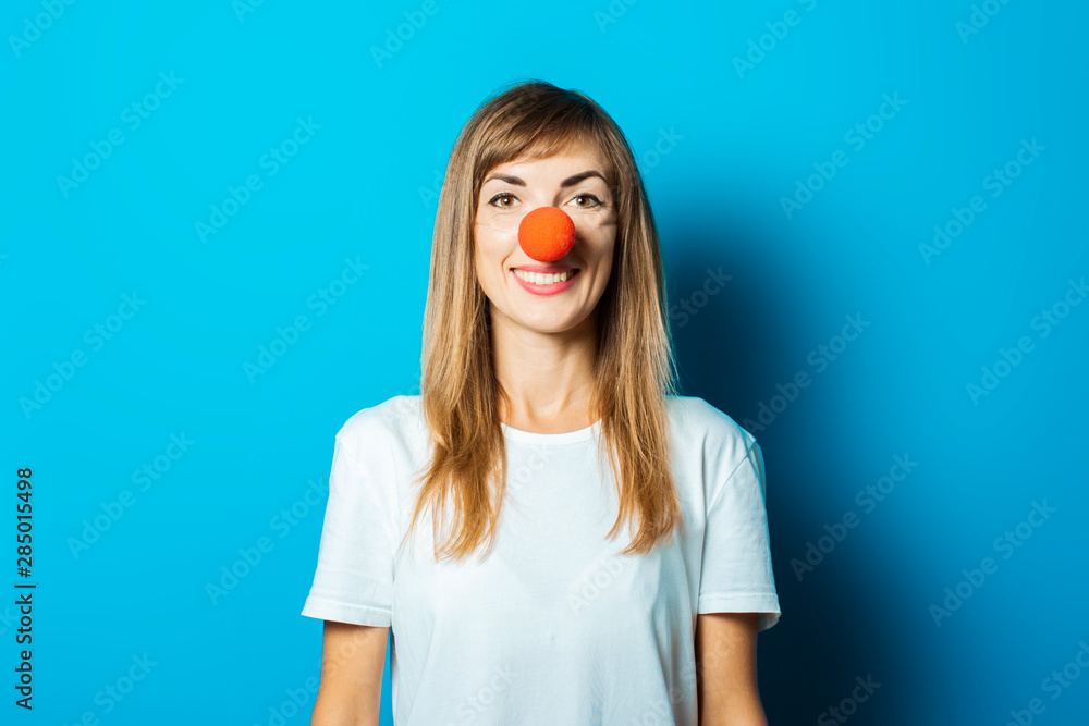 Beautiful young woman in a white T-shirt and red nose of a clown on a ...