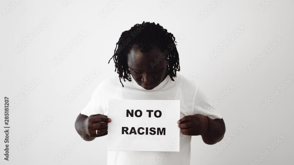 Black man in despair holding a say no to racism message, portrait shot ...