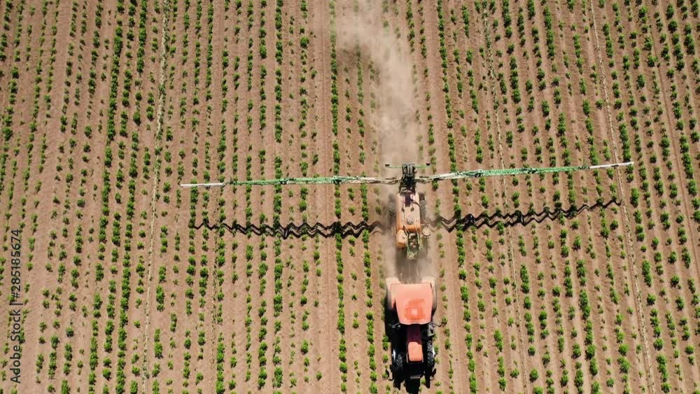 Tractor spraying glyphosate pesticides on farm field from above.Tractor ...
