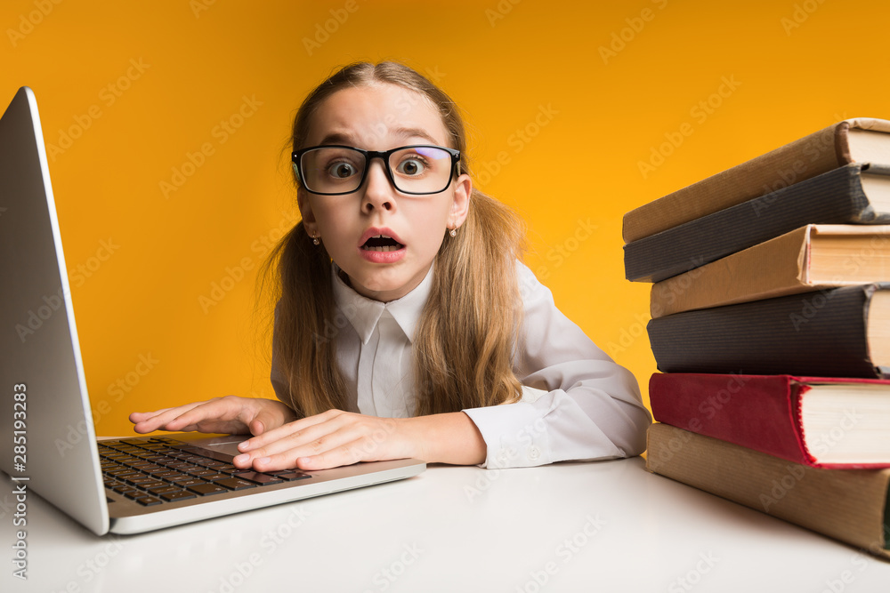 Surprised First-Grade Schoolgirl Doing Homework On Laptop, Yellow ...