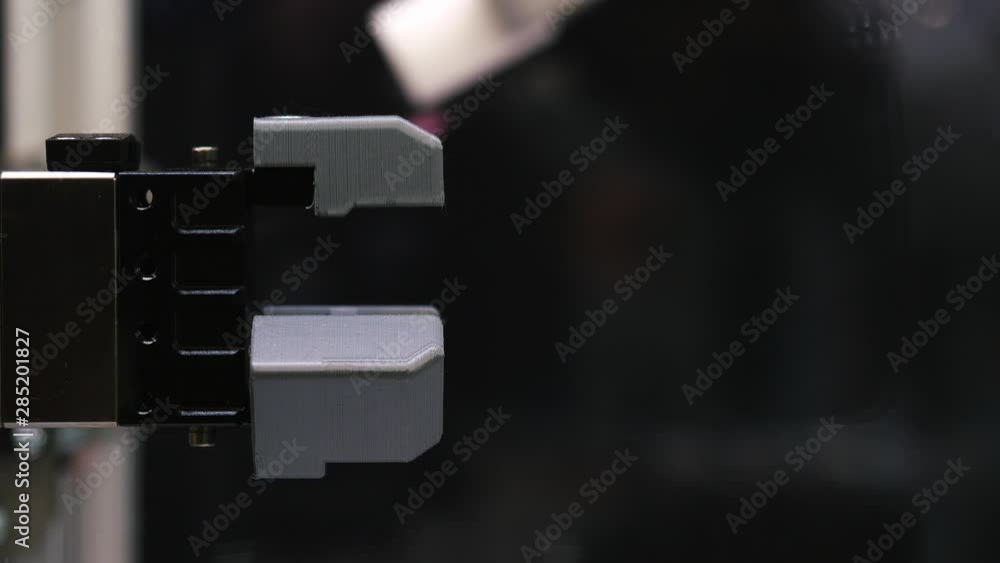 Close-up of two robot machines holding and relocating some small white ...