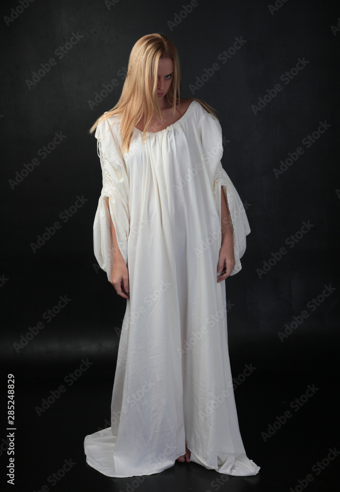 full length portrait of blonde girl wearing long white flowing robe ...