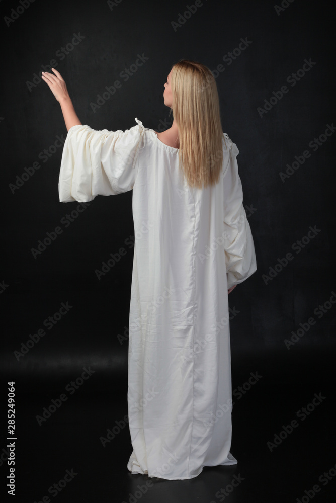 full length portrait of blonde girl wearing long white flowing robe ...