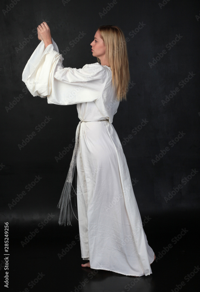 full length portrait of blonde girl wearing long white flowing robe ...