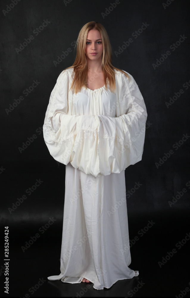 full length portrait of blonde girl wearing long white flowing robe ...