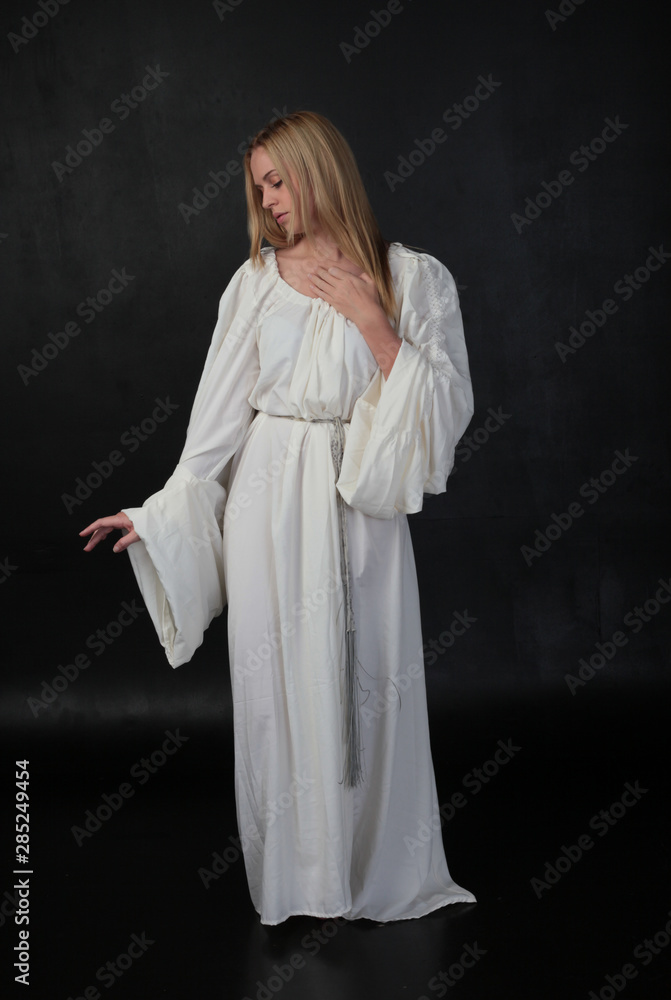 full length portrait of blonde girl wearing long white flowing robe ...