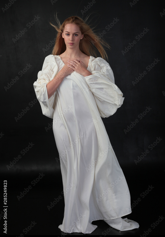 full length portrait of blonde girl wearing long white flowing robe ...