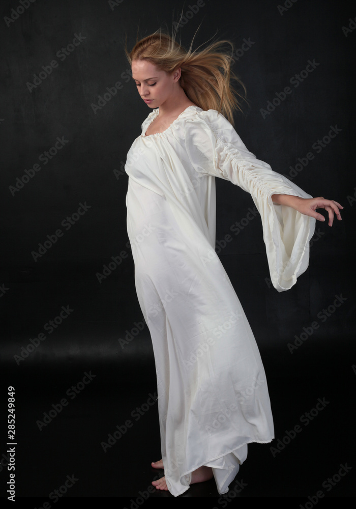 full length portrait of blonde girl wearing long white flowing robe ...