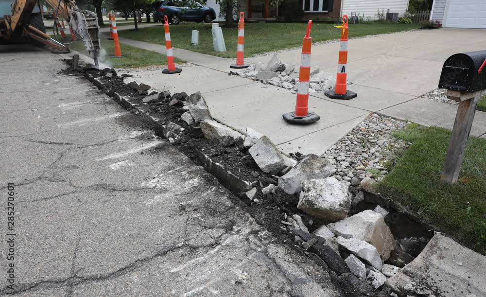A driveway apron is torn up, the first step in replacing it. Stock ...