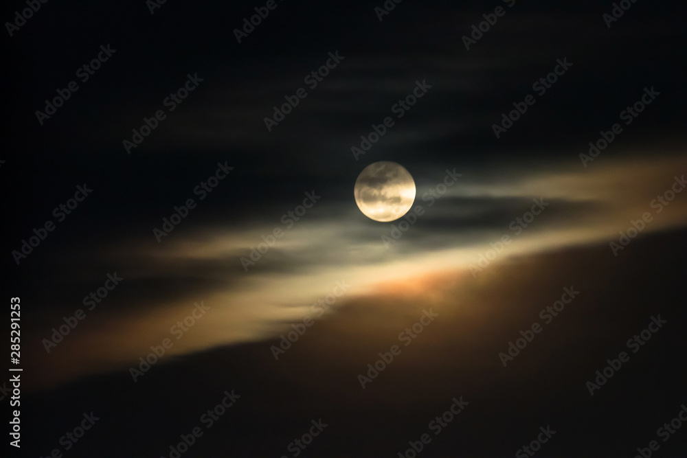 Super moon shining glowing light through the darkness of cloudy night ...