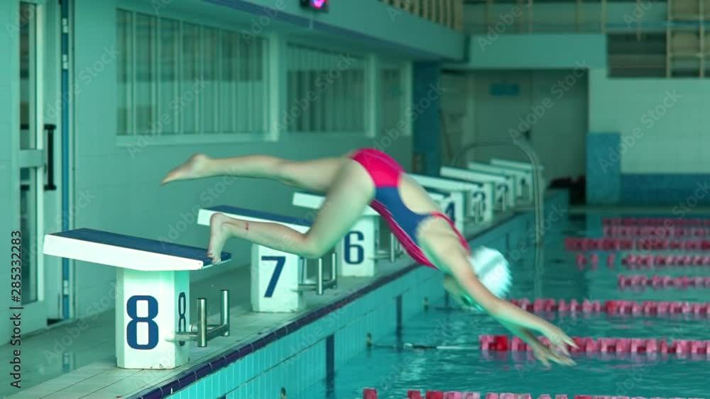 Teenager girl Swimmer Dive In Swimming Pool. Female swimmer dives in ...