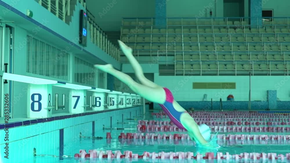 Teenager girl Swimmer Dive In Swimming Pool. Female swimmer dives in ...