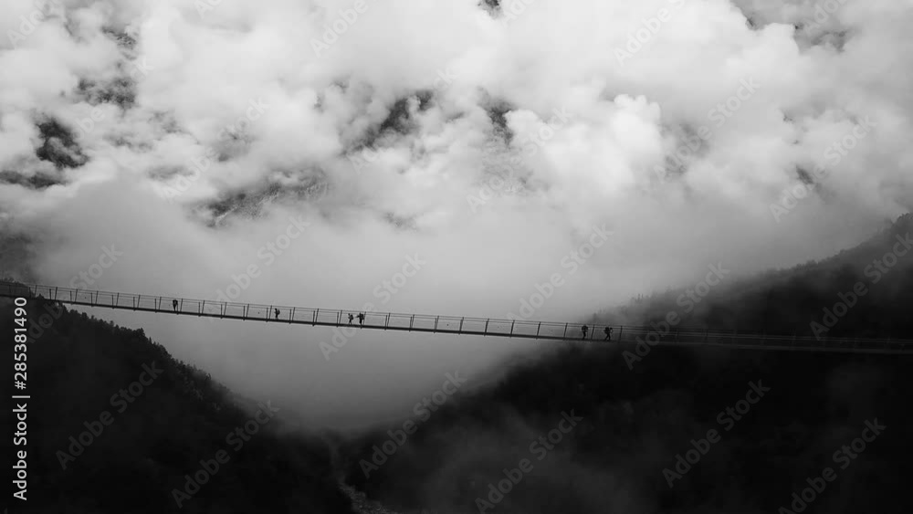 Scenic aerial profile side view of people walking on suspension bridge ...
