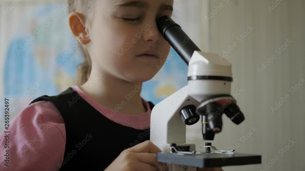 Child looking into microscope, studying biology, chemistry in school ...