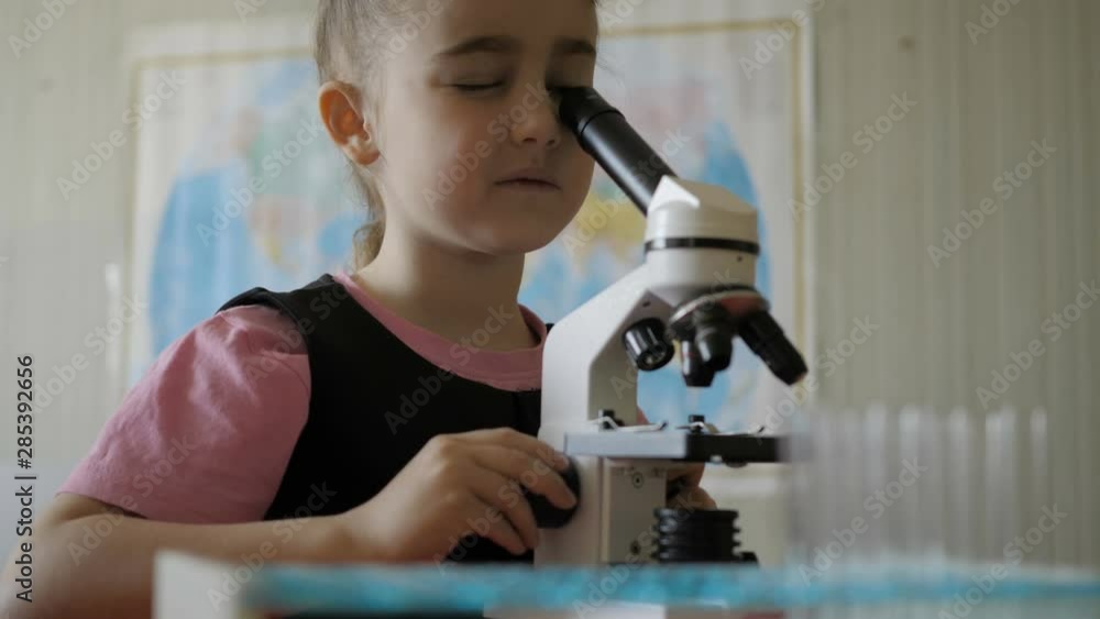 Child looking into microscope, studying biology, chemistry in school ...