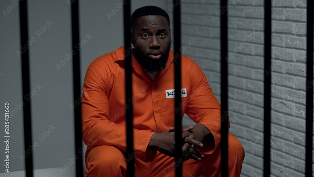 Frightened black prisoner sitting in cell, human rights protection ...