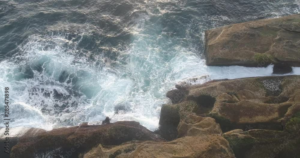 View from above the rocks and the sea colliding, splashing and twirling ...