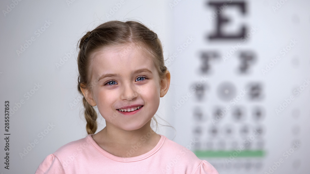 Adorable child girl laughing after vision test on eye chart, healthy ...