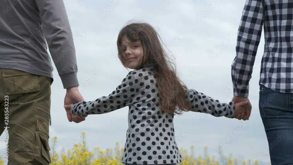 The child holds the hands of parents. Happy little girl holds the hand ...