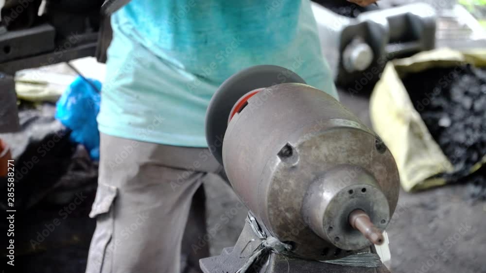 Sharpening the machete on sharpening machine. Worker sharpening machete ...