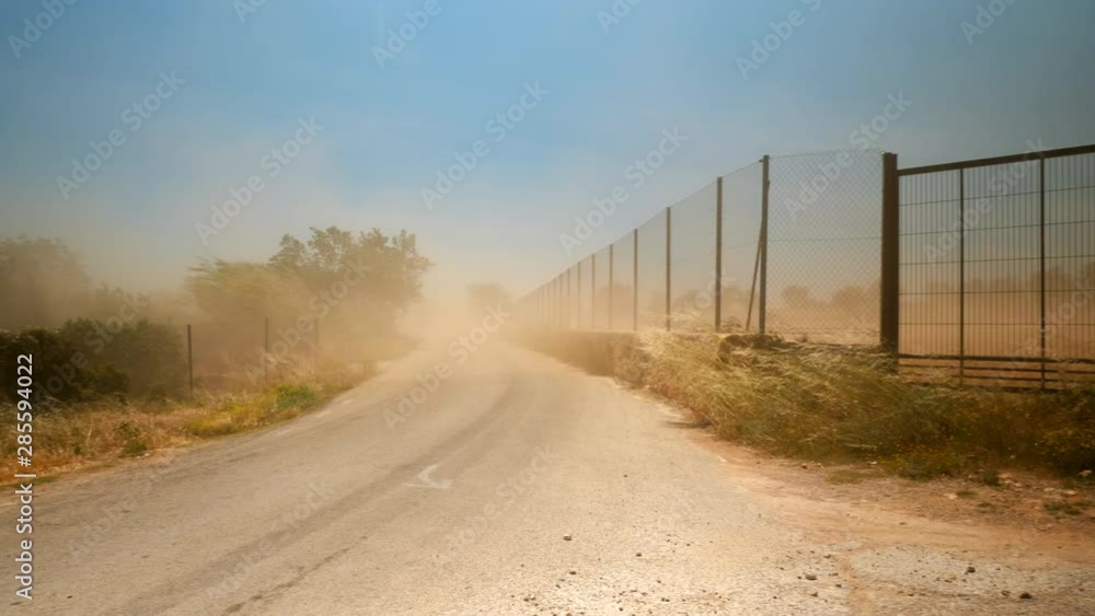 Heavy sandstorm with strong wind blowing dust on empty road in dry area ...
