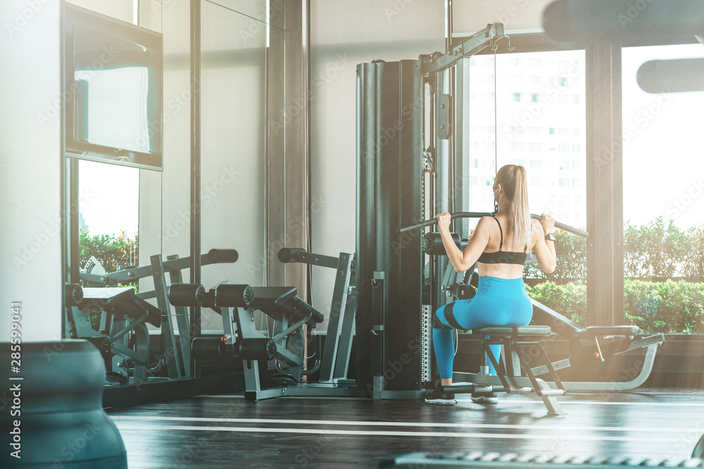 Exercise your body. Fitness girl exercising on lat machine. Copy space ...