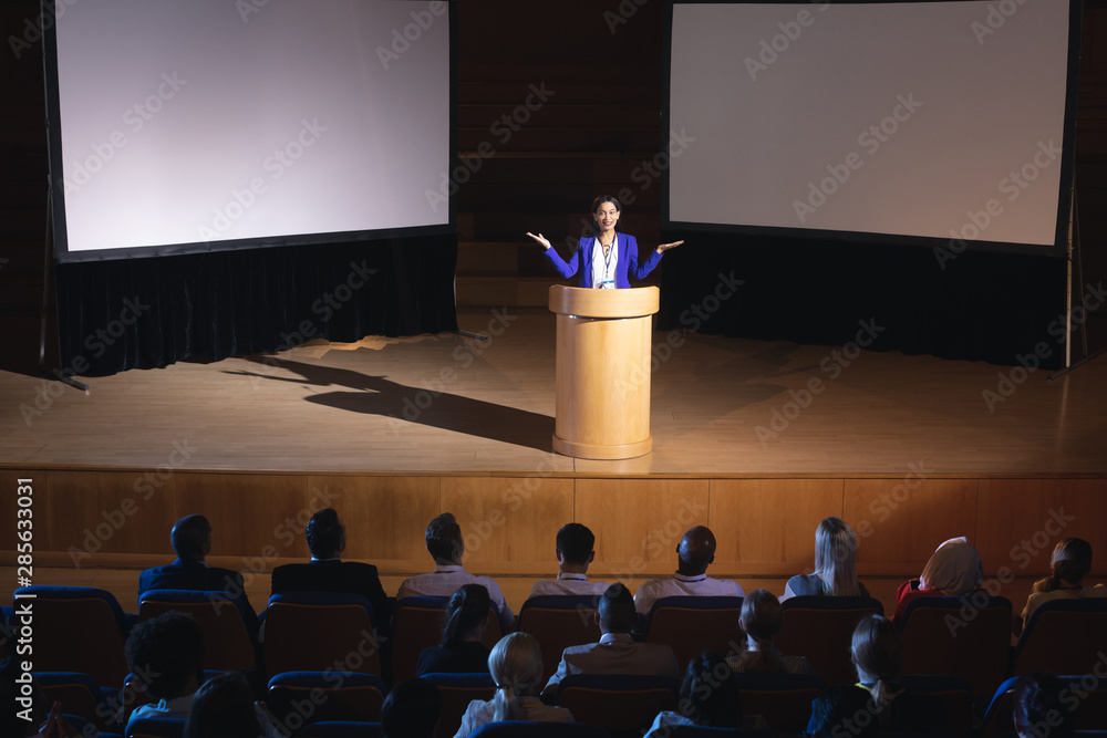 Businesswoman standing around podium and giving presentation to the ...