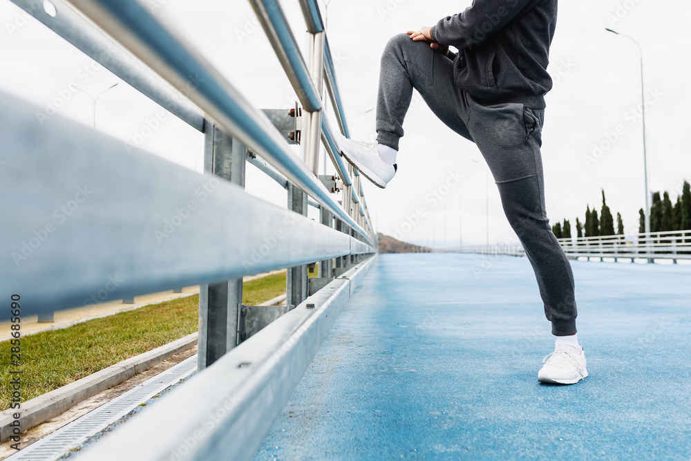 Side view - a handsome slender young man in a gray tracksuit kneads the ...