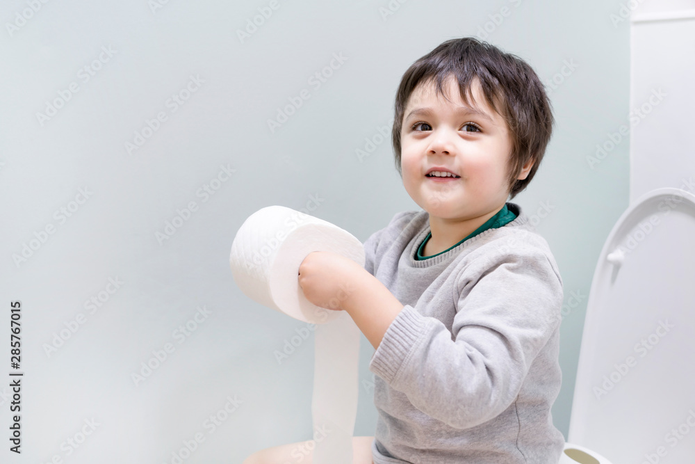 Happy boy playing with white toilet paper in toilet, Healthy kid ...