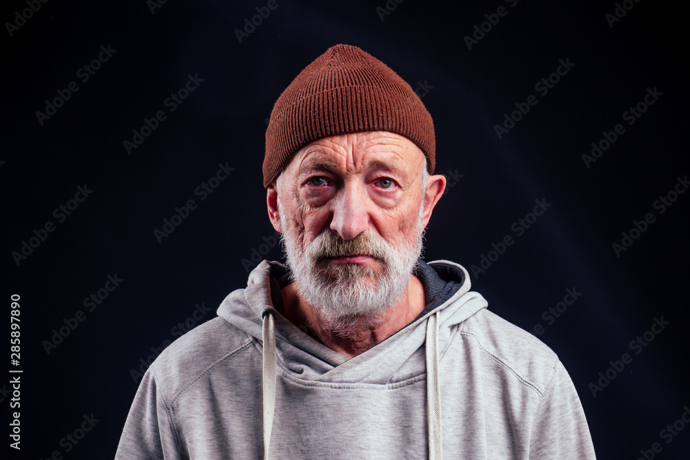 Poster portrait of sad old senior male tramp wearing warm brown hat and ...