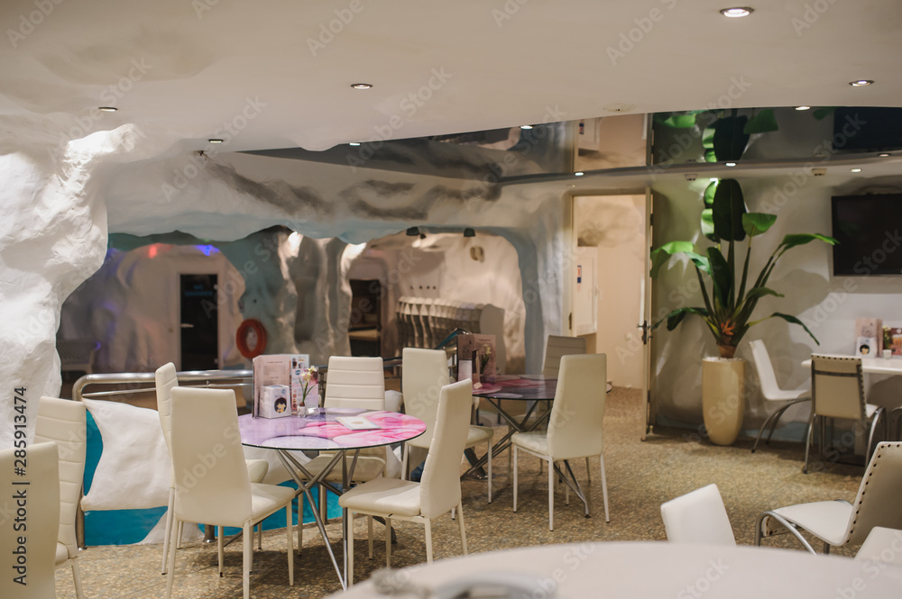 the interior of a fito bar in a spa centre: white tables and chairs ...