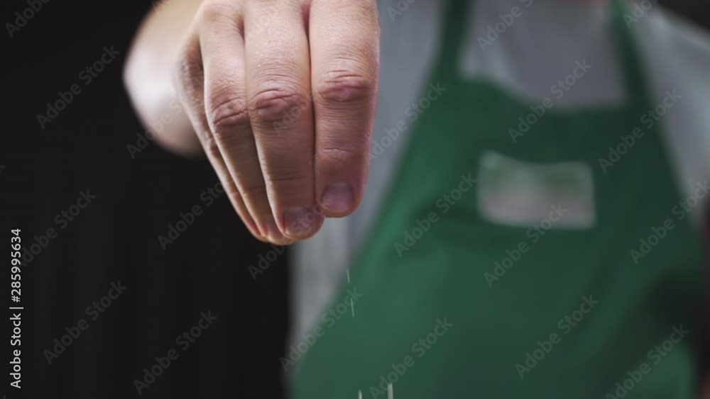 Close up shot: chef adds coarse salt to the dish, cooking in slow ...