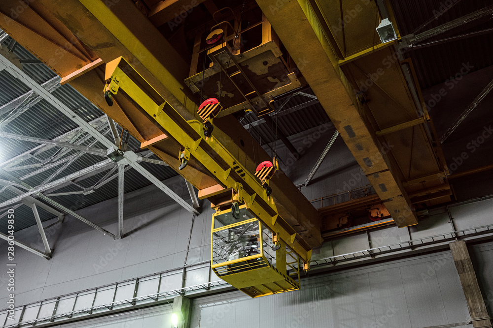 Yellow overhead crane with linear traverse and hooks in engineering ...