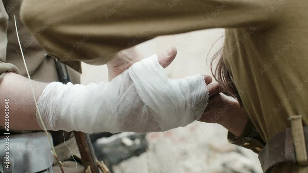 Handheld shot dressing the wounded. Close-up of nurses and soldiers in ...