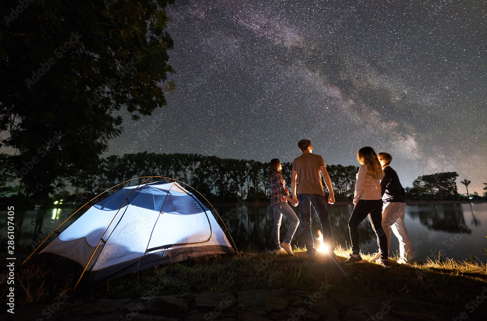 Night camping on lake shore near campfire. Two couple having a rest ...