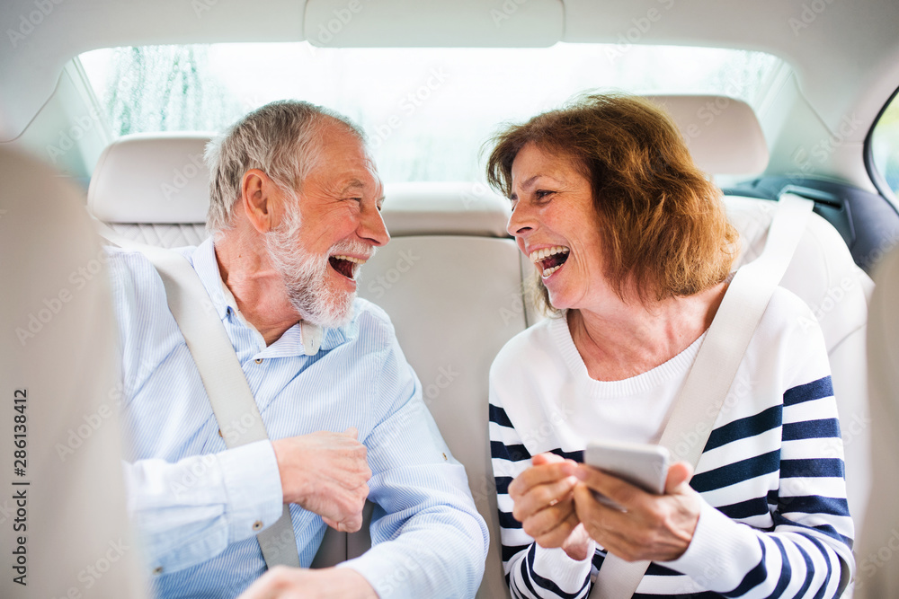 Cheerful senior couple sitting on back seats in car, laughing. Stock ...