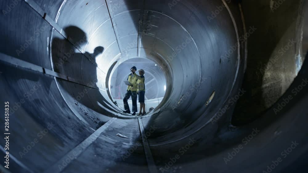 Two Heavy Industry Engineers Walking Inside Pipe, Use Laptop, Have ...