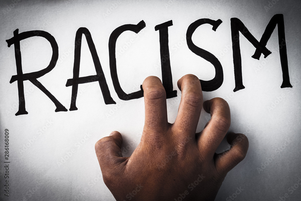 African child hand scratches the word racism. No to racism. Symbol of ...