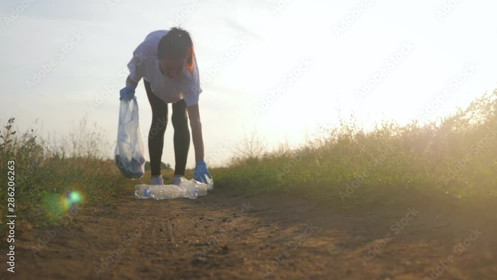 Care about nature. Volunteer girl collects trash in the trash bag ...