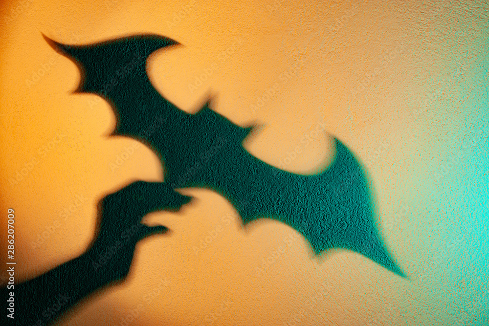 Hand holding a bat. Shadow reflection on the wall. Shadow theater. The ...