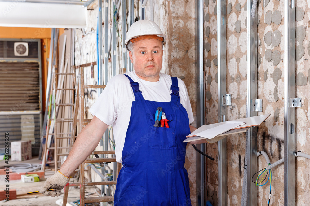 Scared and confused male contractor looking at room and determining ...