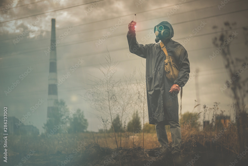 Man in gas mask is looking a radioactive liquid in vial in his hand on ...