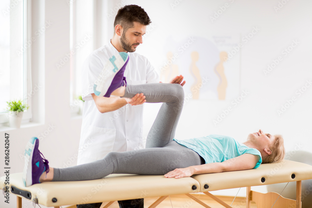 Middle age woman with knee injury lying on physiotherapy table during ...